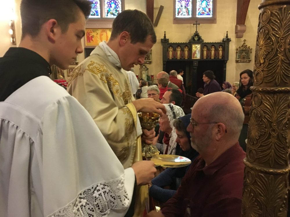 Father Luke DeMasi gives Communion during his first Mass at Our Lady of ...