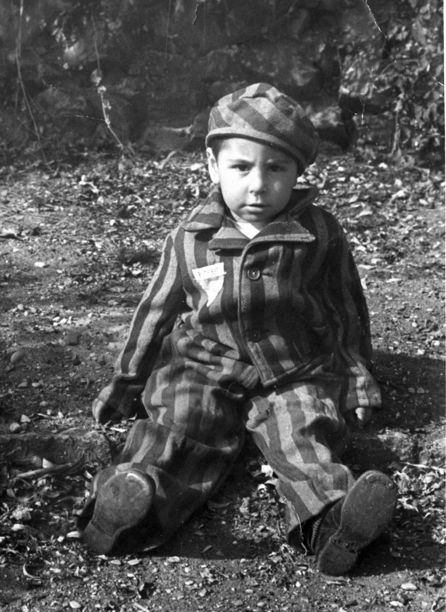 A boy wears a prisoner’s uniform after the liberation of the Nazi death ...