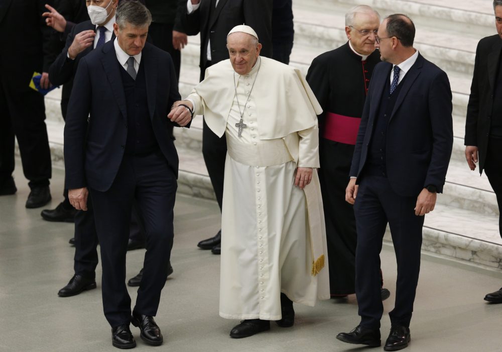 Pope Francis holds the arm of his aide, Sandro Mariotti, as he walks ...