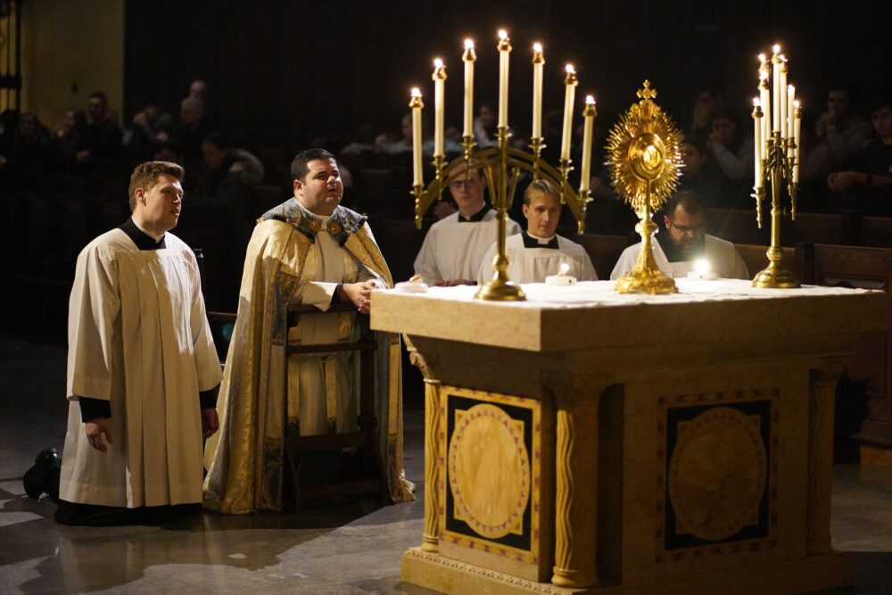 Father Matt Browne is flanked by seminarians as he presides at a “Holy ...
