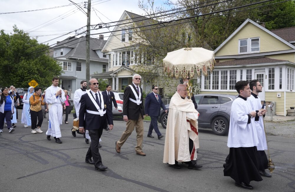 Father Roger Landry carries the monstrance as a Eucharistic procession ...